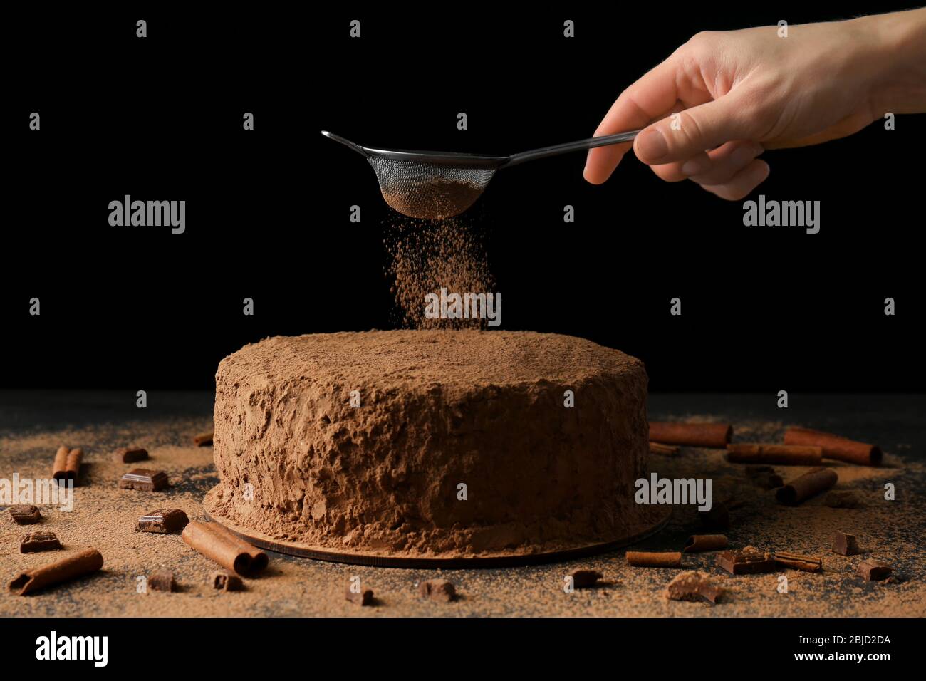 Woman powdering chocolate cake with cocoa powder Stock Photo - Alamy