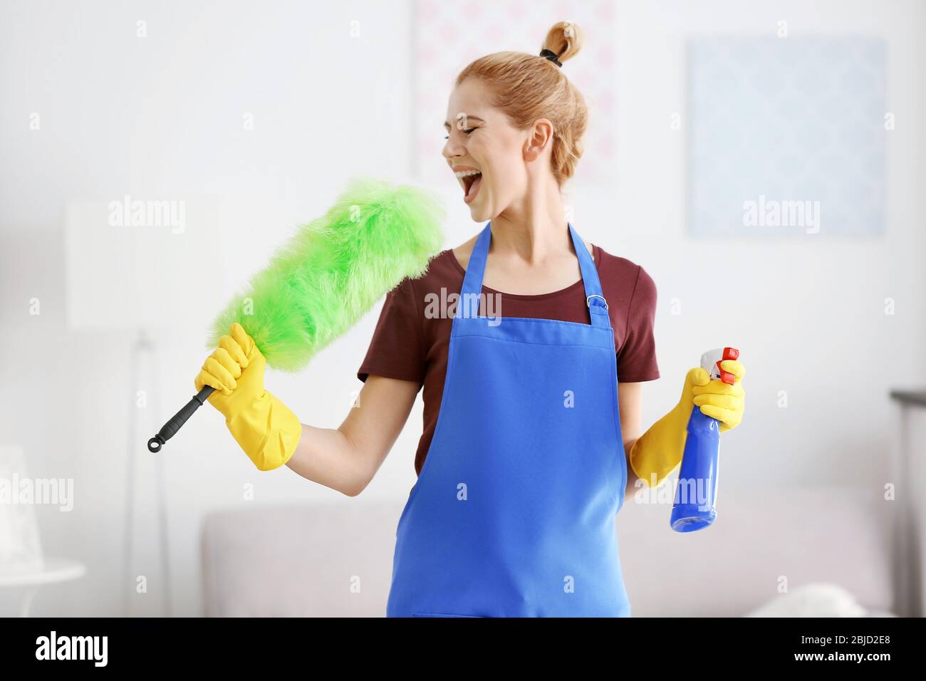 Funny adult woman with duster and detergent in living room Stock Photo ...