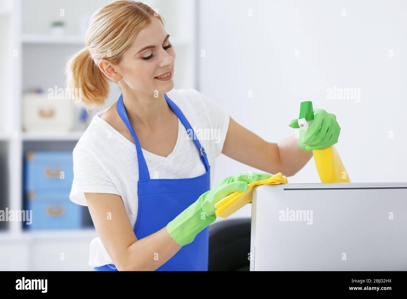 Pretty adult woman wiping computer in office Stock Photo - Alamy