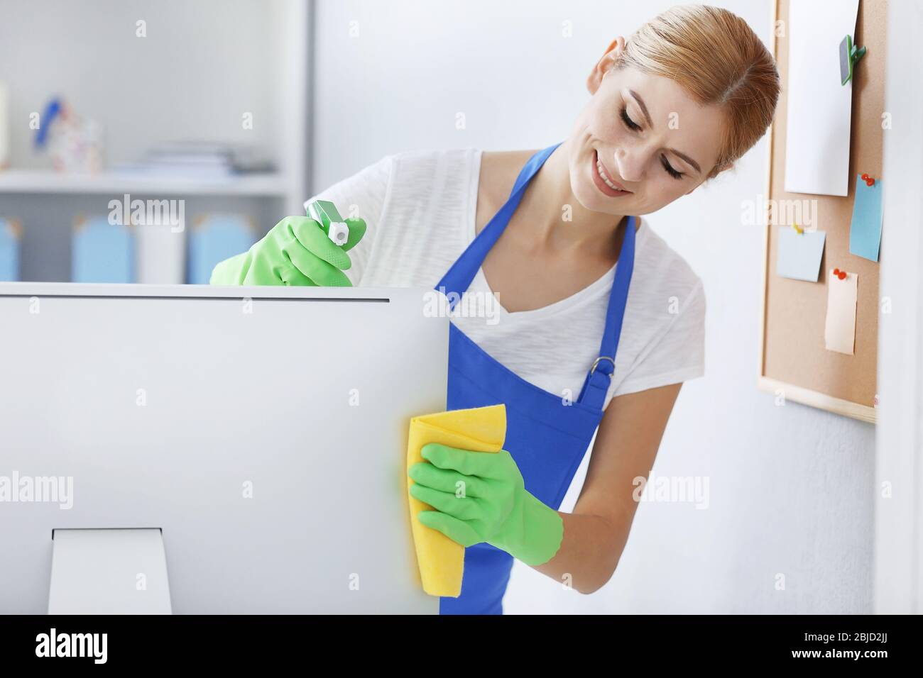 Pretty adult woman wiping computer in office Stock Photo - Alamy