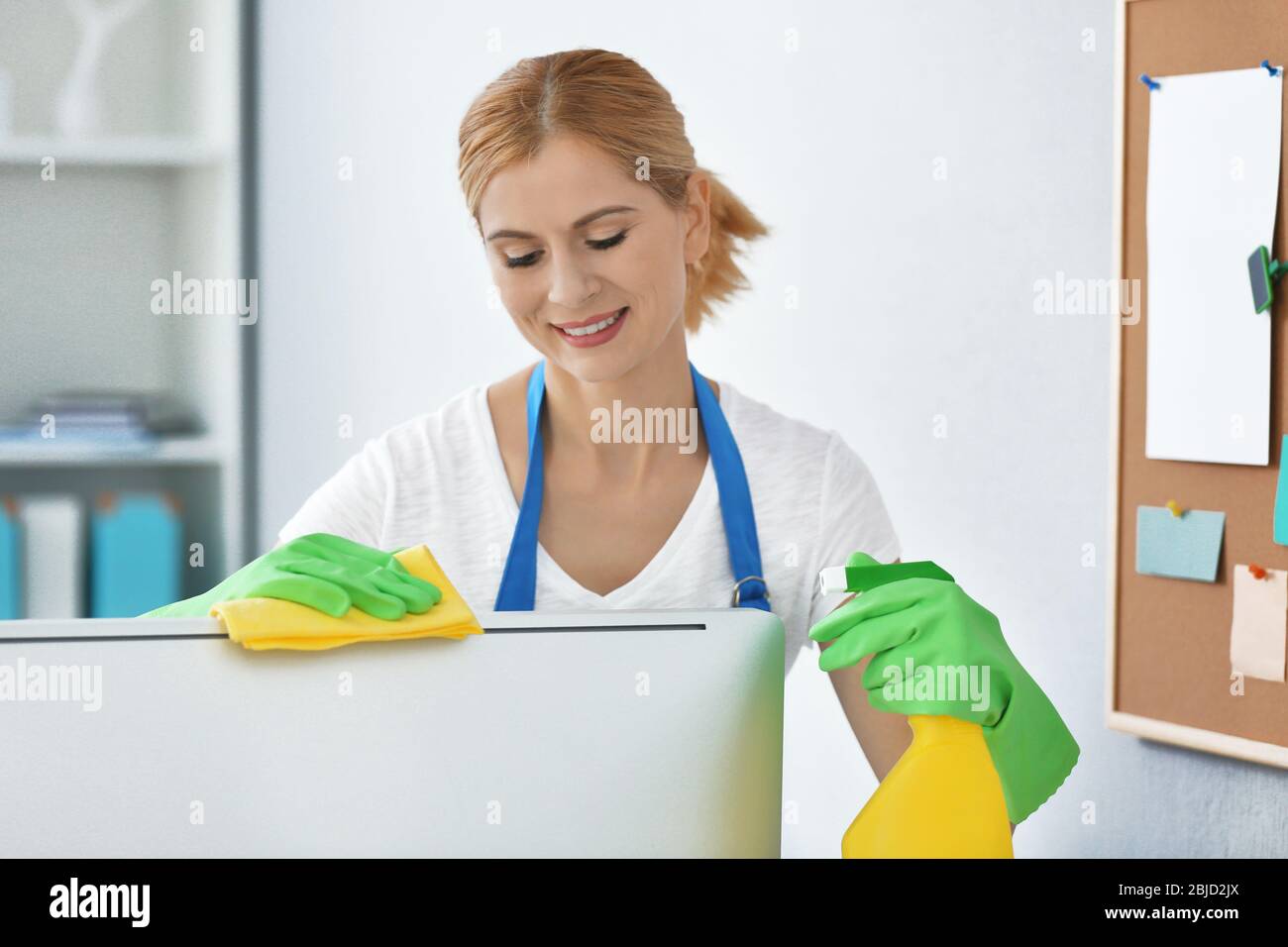 Pretty adult woman wiping pc monitor in office, close up Stock Photo ...