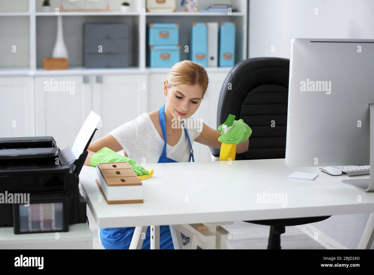 Pretty adult woman wiping table in office Stock Photo - Alamy