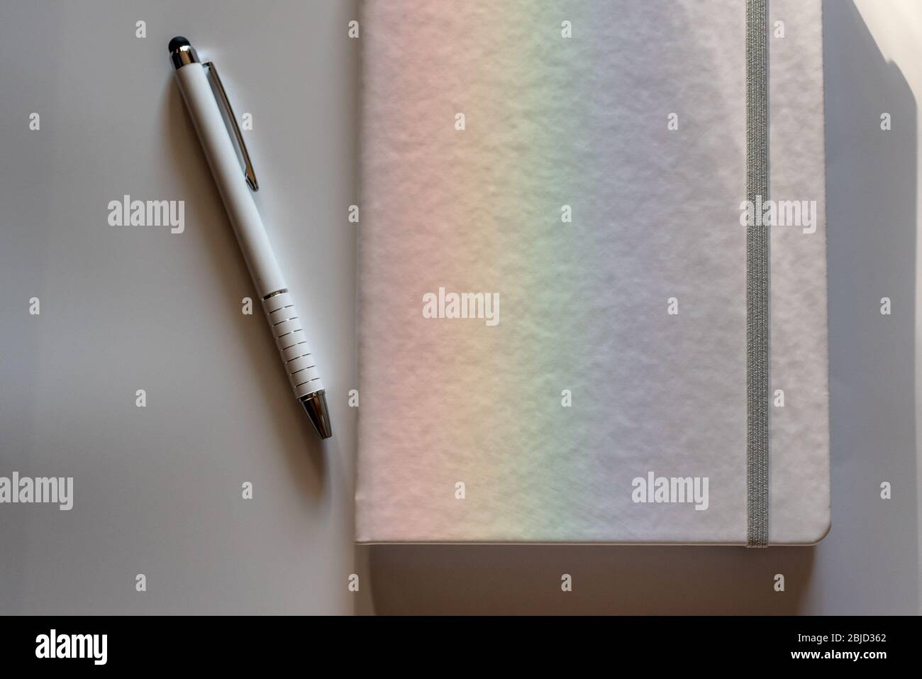 White Notebook & Pen on white surface lit by a light dispersed into ...