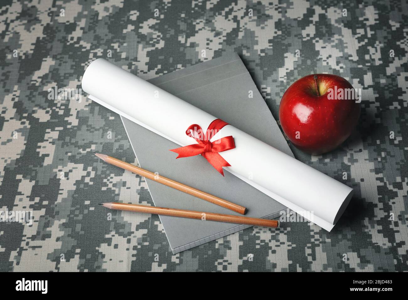 Military education concept. Notebook, pencils, scroll paper and apple ...