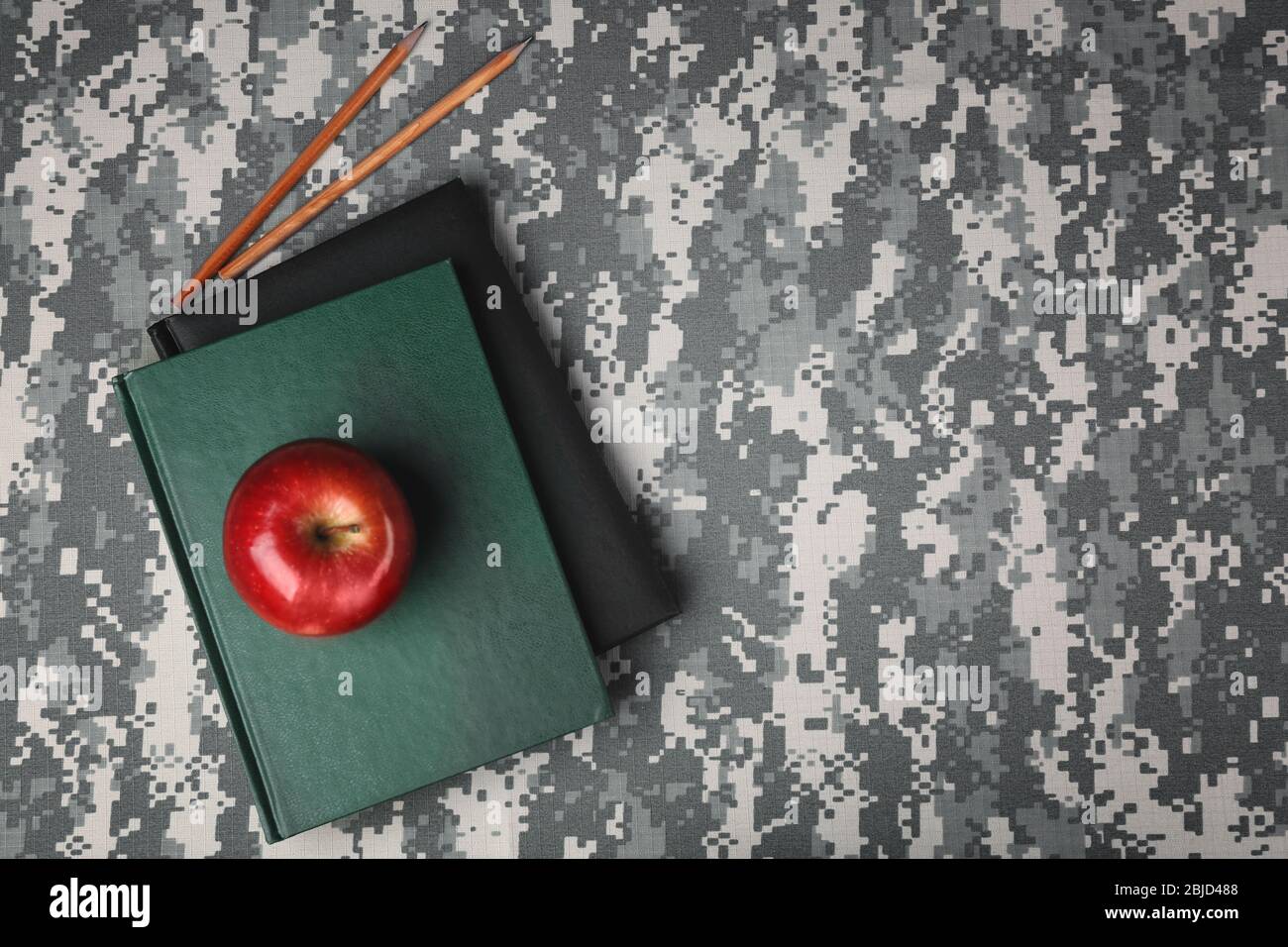 Military education concept. Books, pencils and apple on camouflage ...
