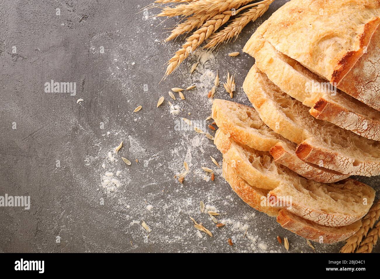 Sliced bread with wheat spikes and flour on grey table closeup Stock ...