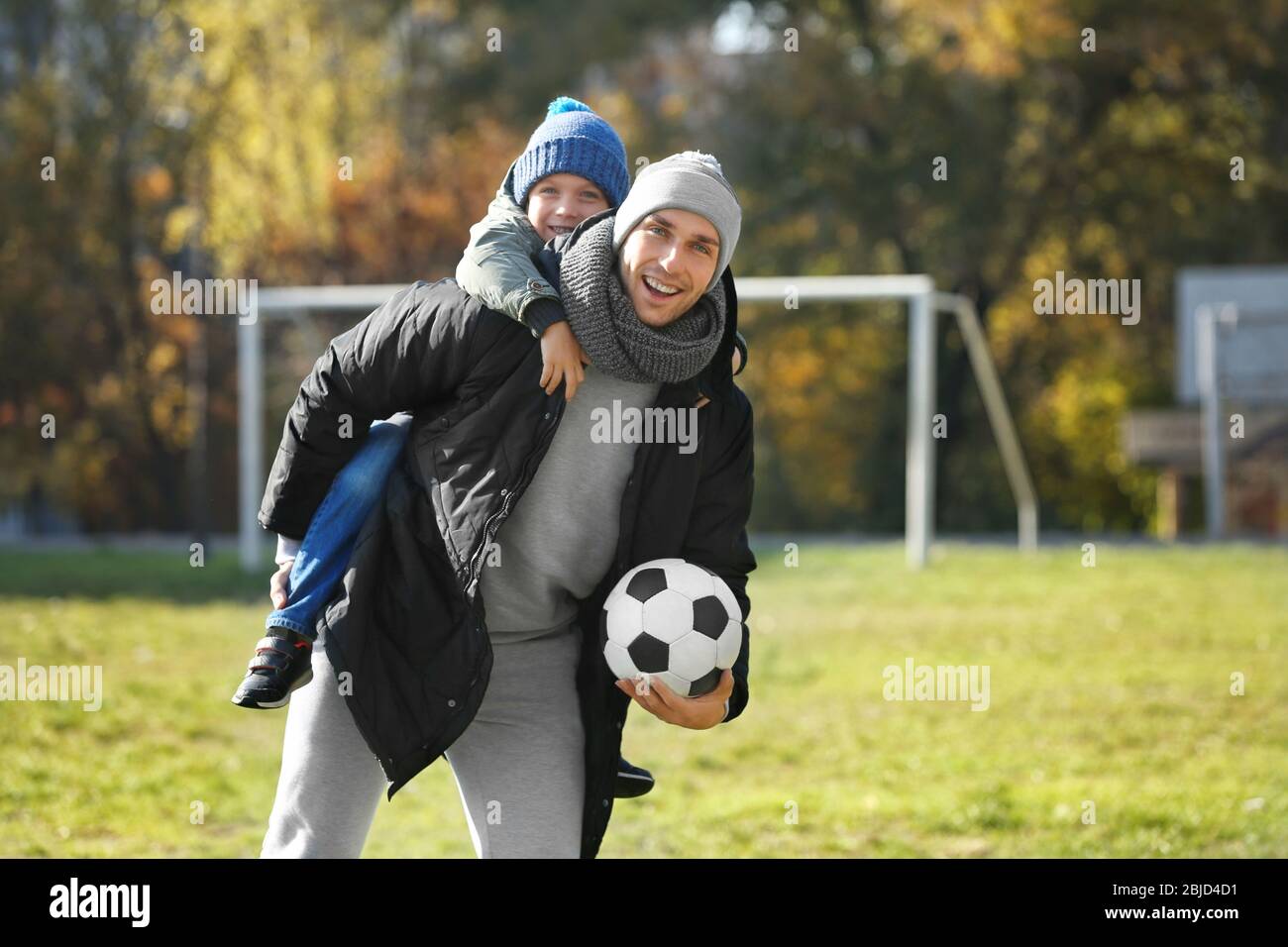 Father and son with ball on soccer pitch Stock Photo - Alamy
