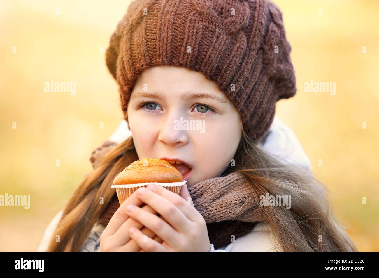 Cute little girl eating tasty muffin outdoors, close up view Stock ...