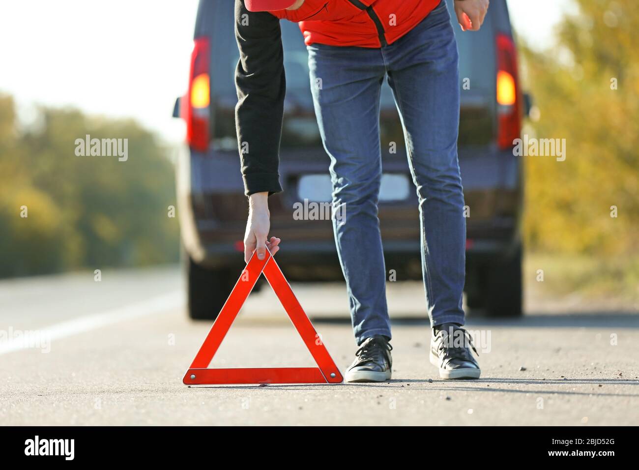 Driver putting warning triangle on asphalt road. Emergency stop concept ...