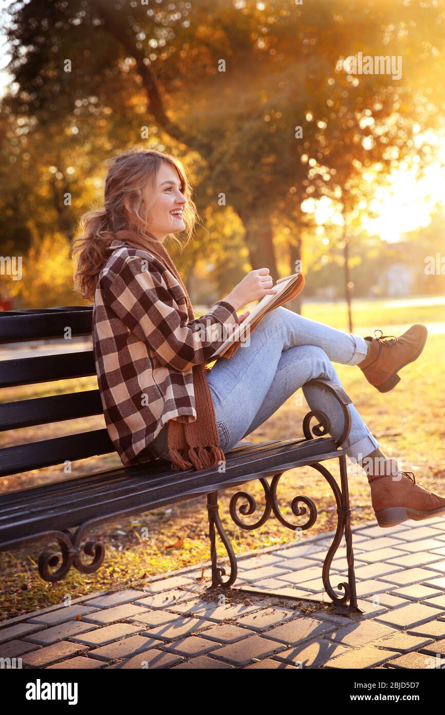 Young female artist drawing sketch while sitting on bench in beautiful ...