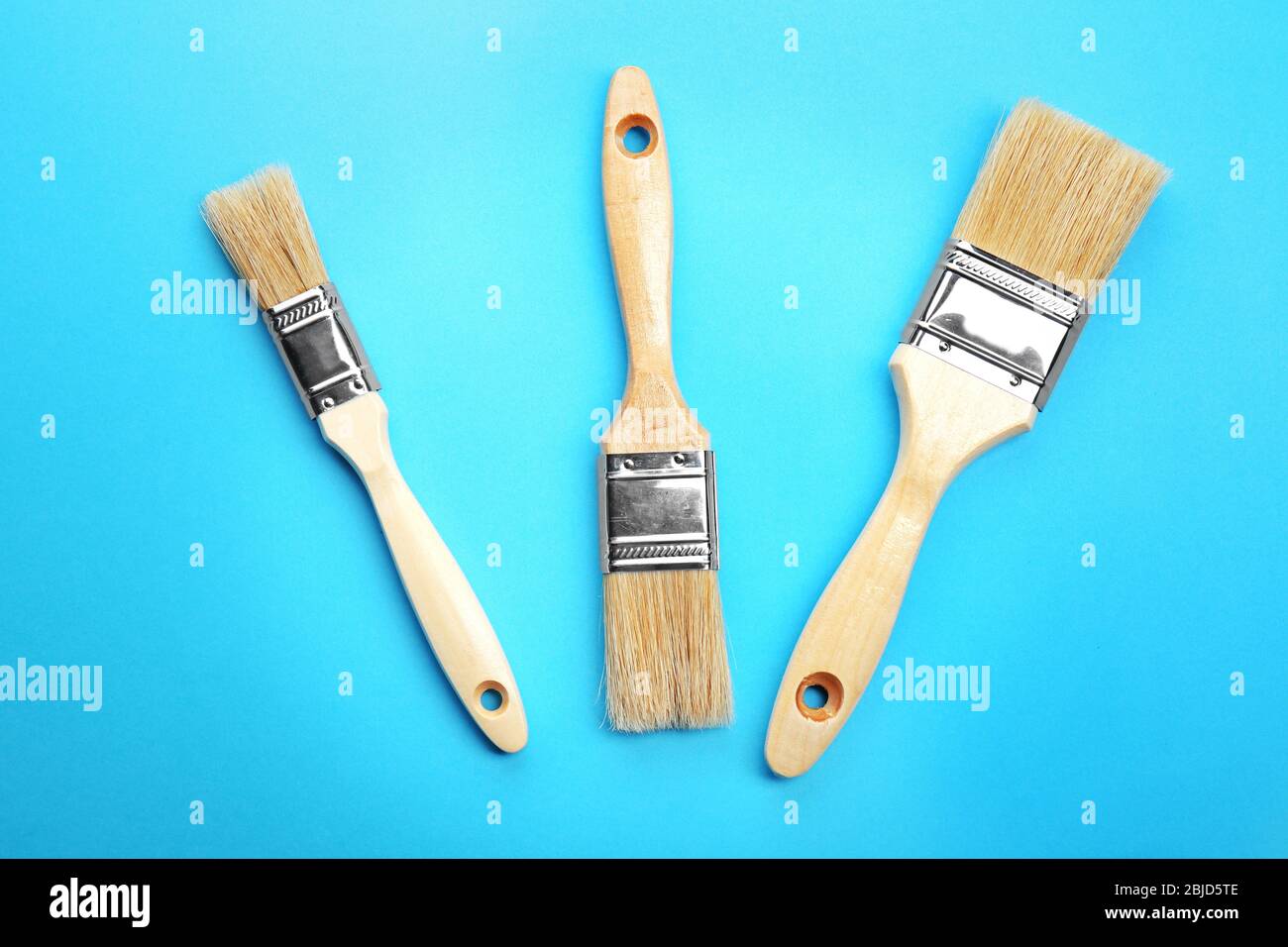 Three painting brushes on blue background Stock Photo - Alamy
