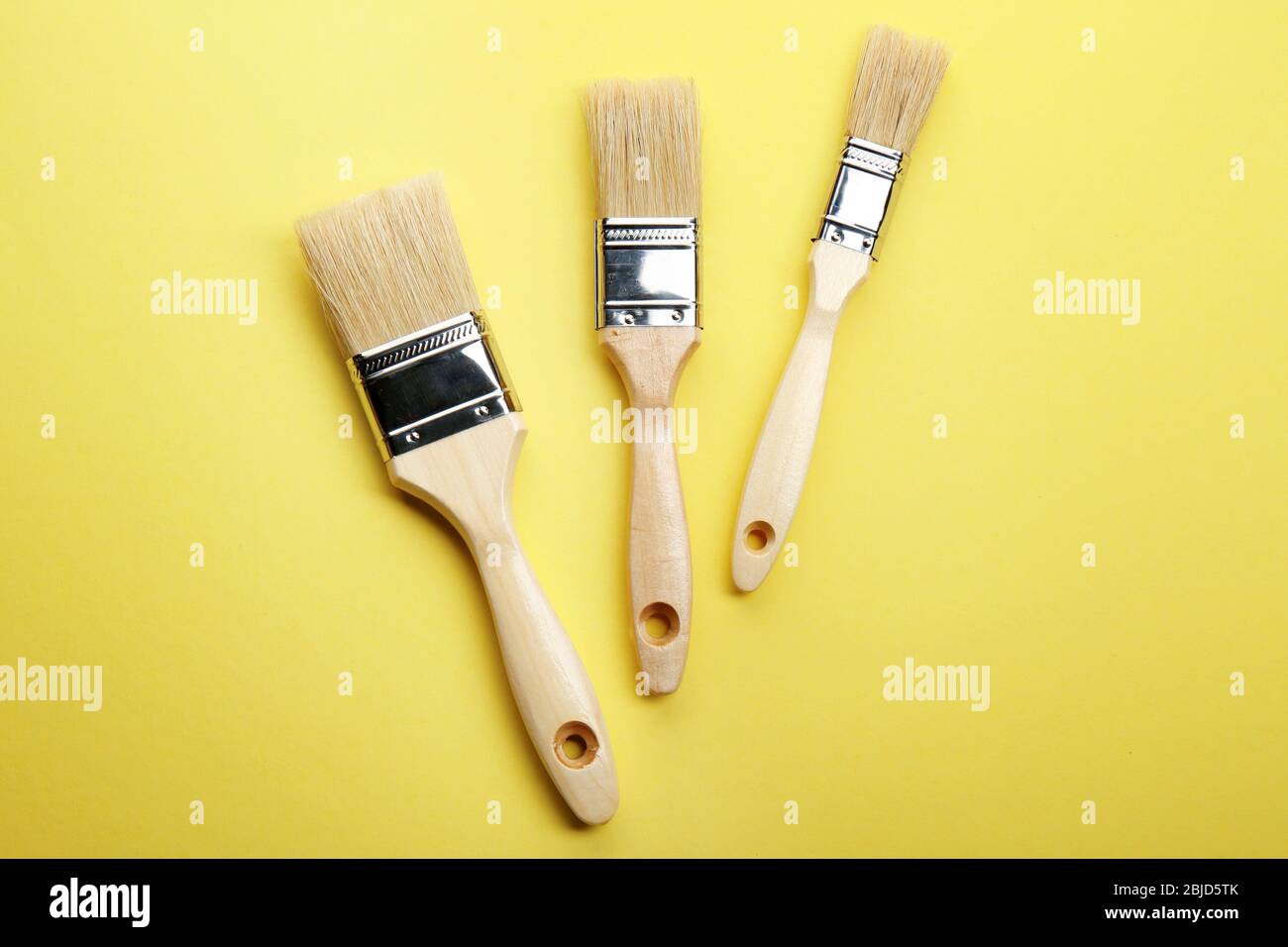 Three brushes on yellow background Stock Photo - Alamy