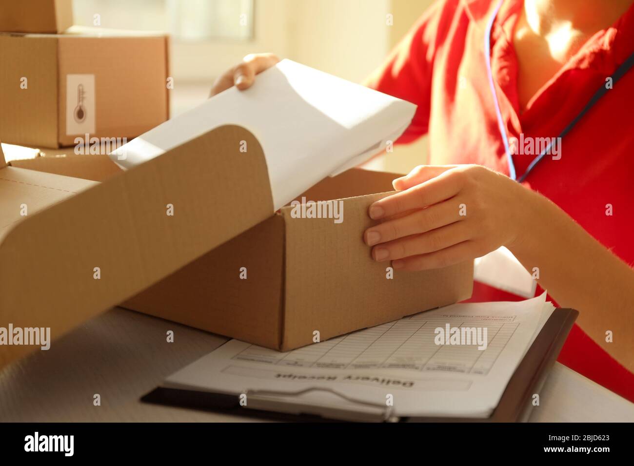 Courier hands packaging parcel at table Stock Photo - Alamy
