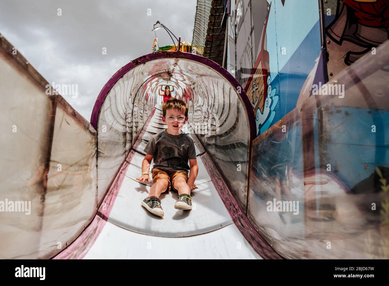 portrait of bored boy sliding down a large slide at county fair Stock ...