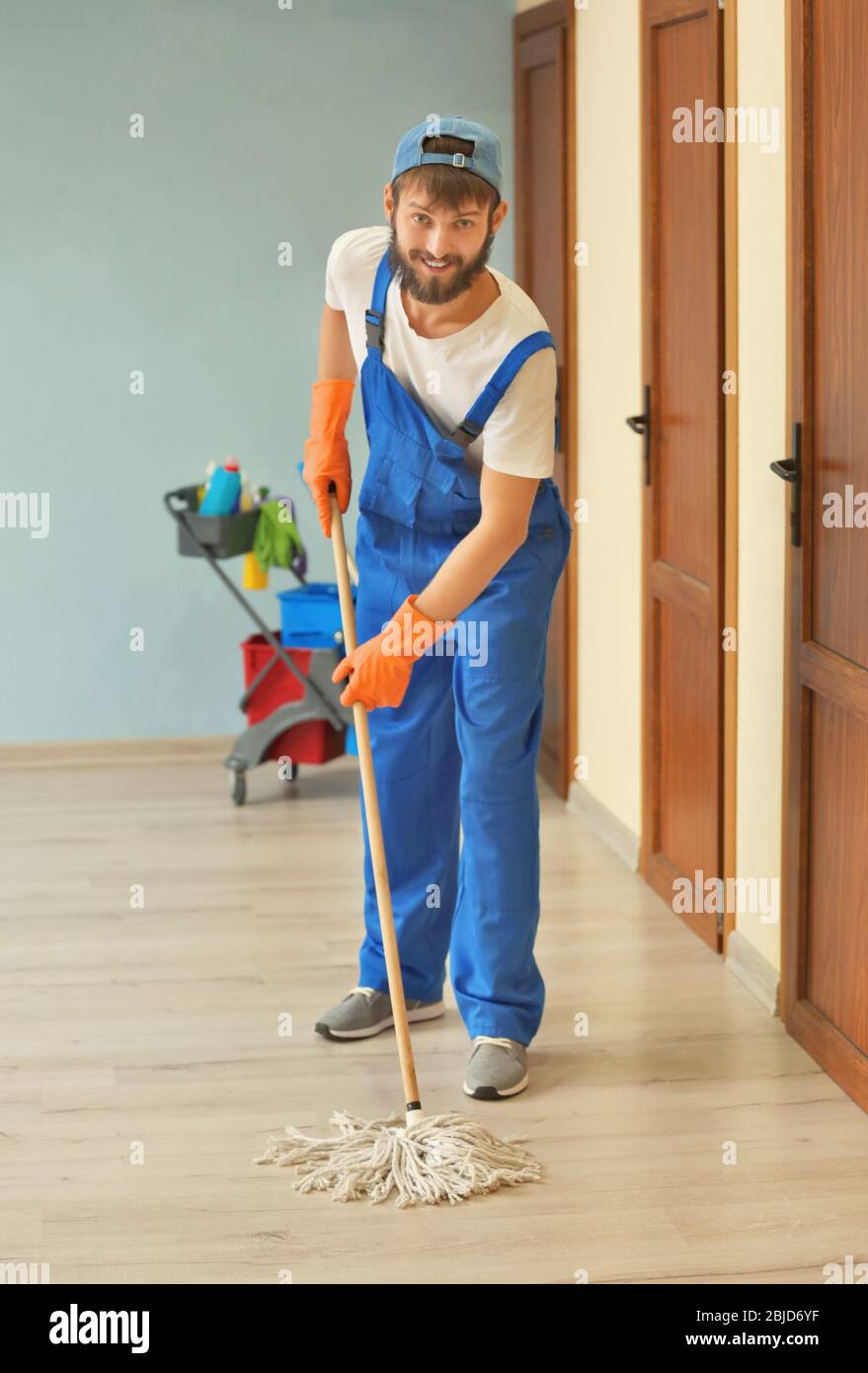 Funny young man moping floor in empty flat Stock Photo - Alamy