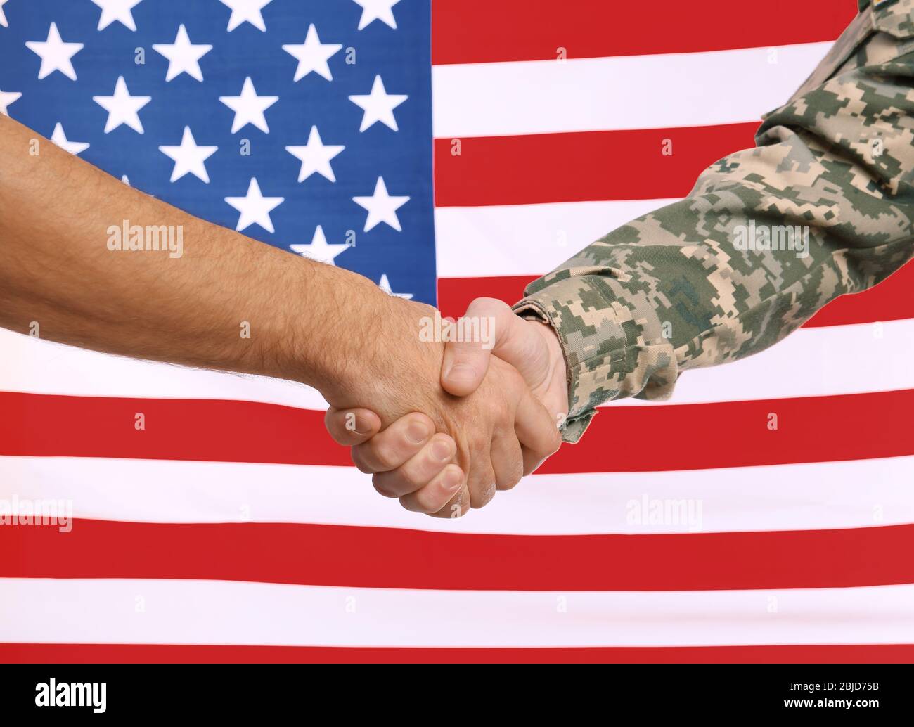 Soldier and civilian shaking hands with USA flag on background ...