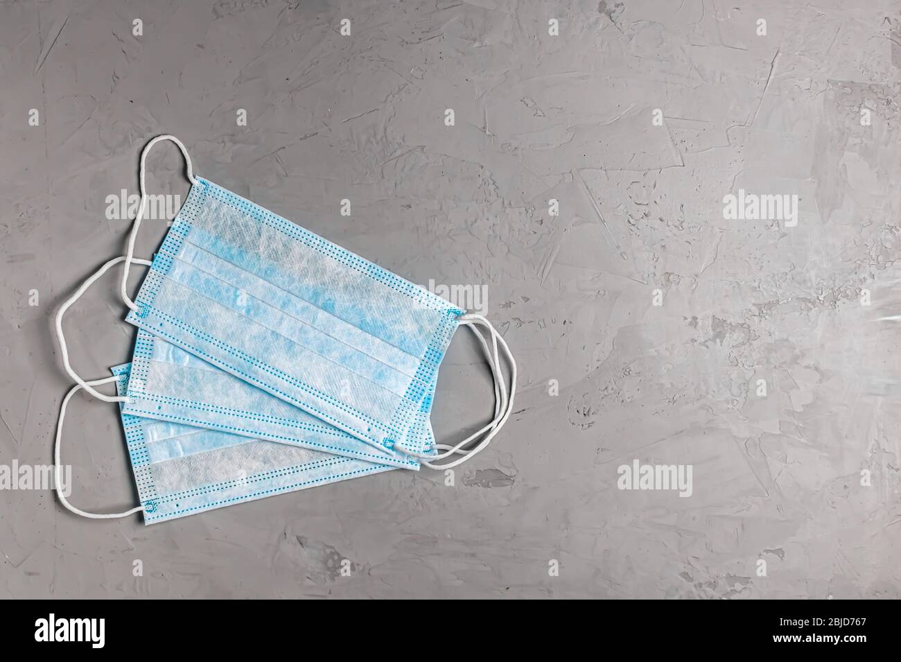 three blue disposable mask on a grey concrete background. flat lay. top ...