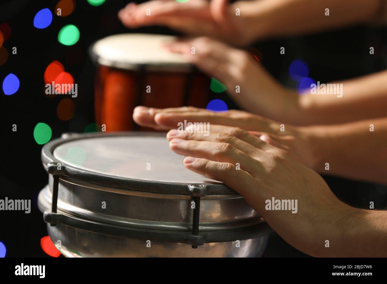 Hands of man playing African drum against defocused lights Stock Photo ...