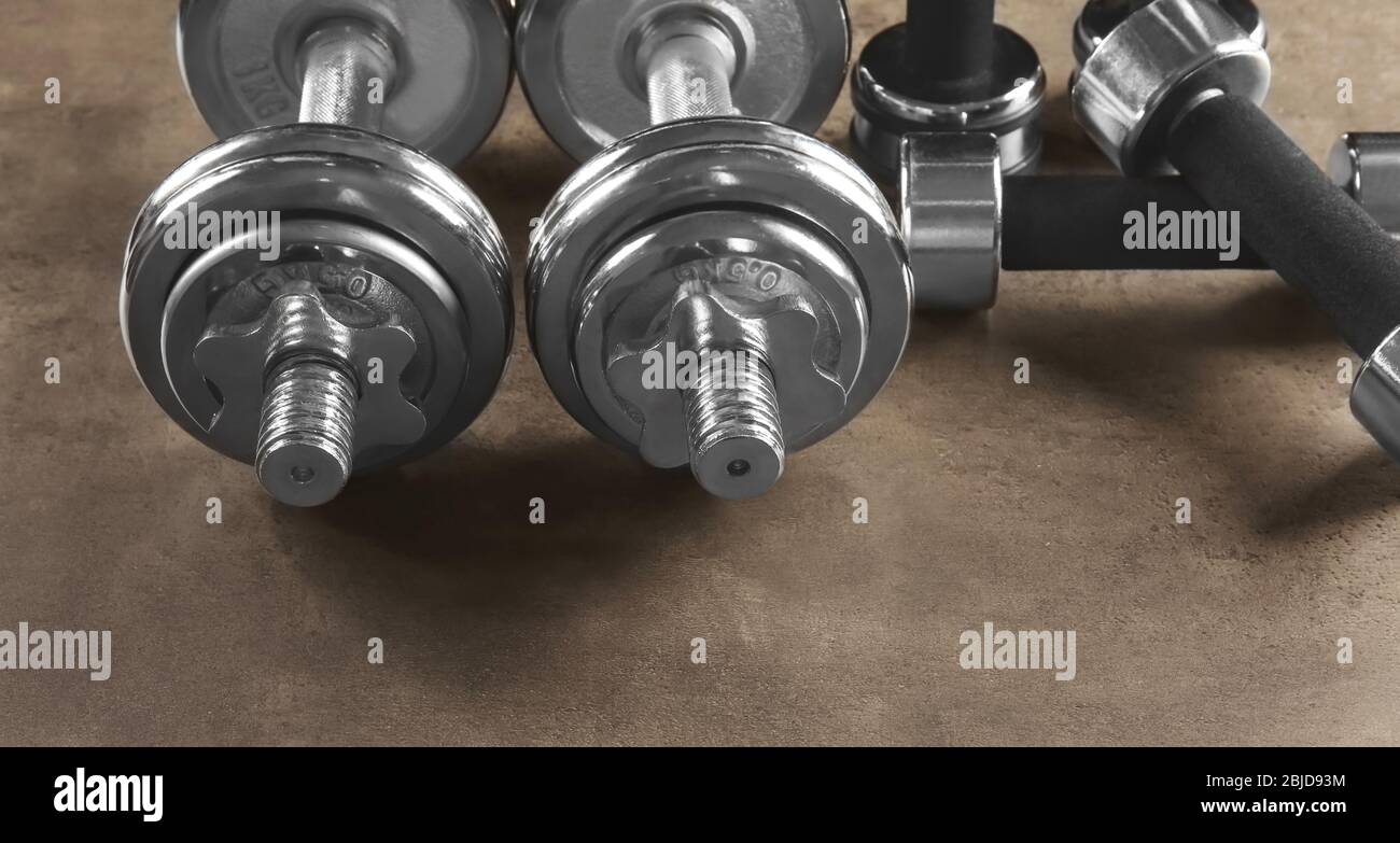 Different dumbbells on grey textured surface Stock Photo - Alamy