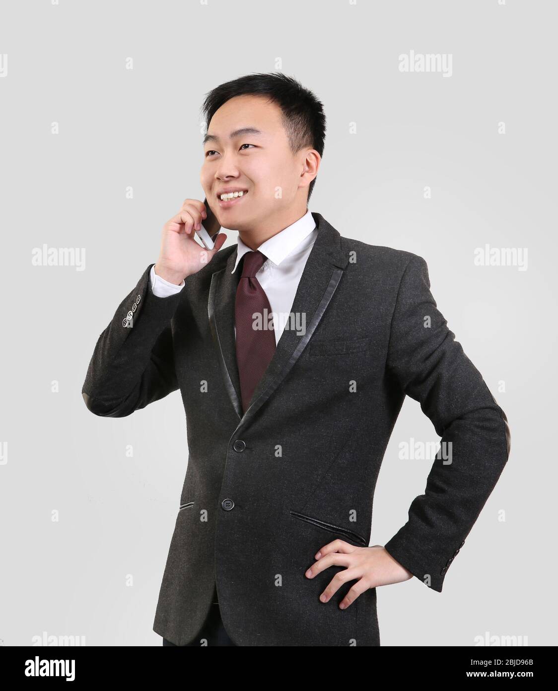 Handsome Asian man talking by mobile phone, on light background Stock ...