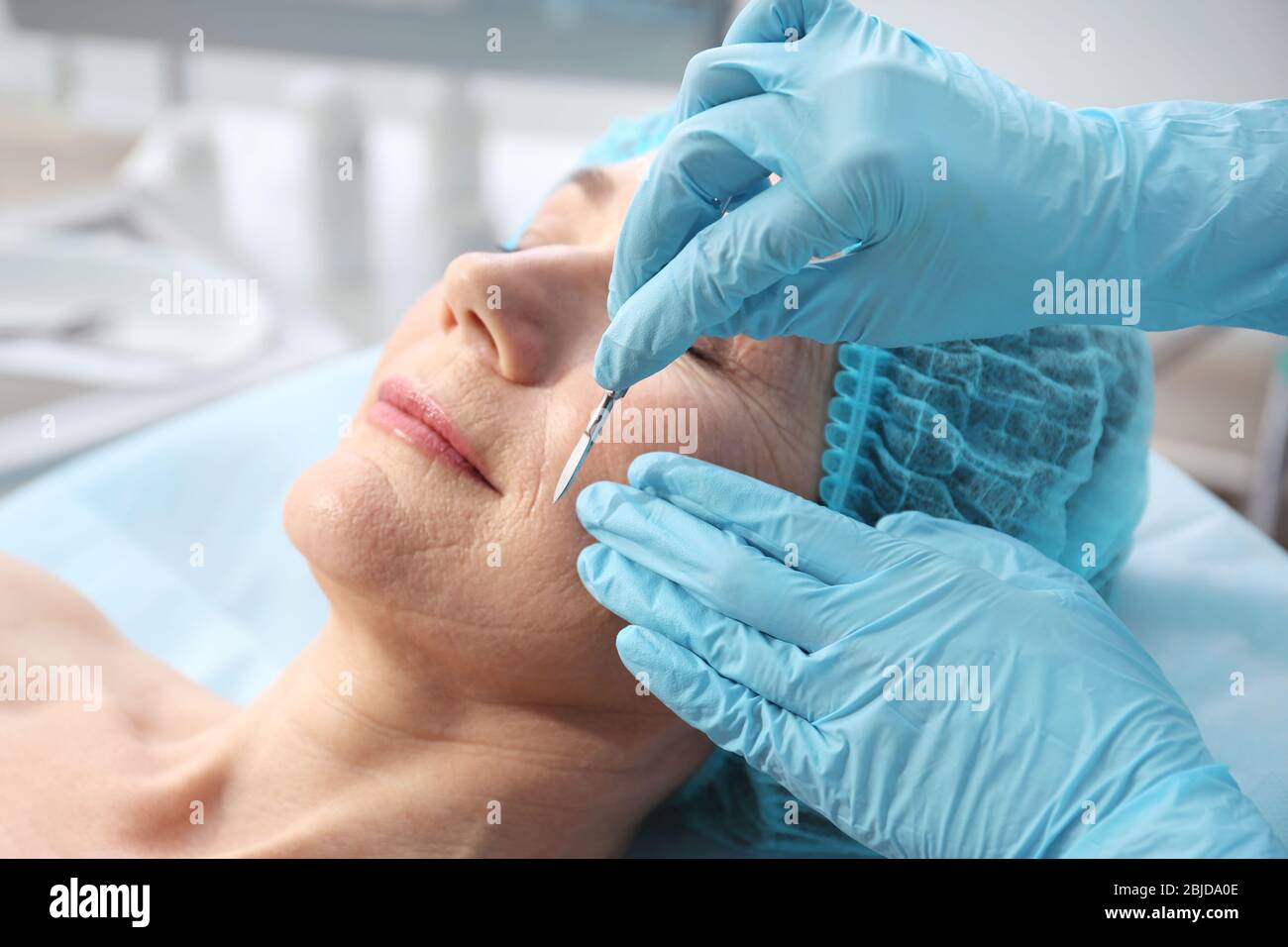 Surgeon operating female patient with scalpel at beauty salon Stock ...