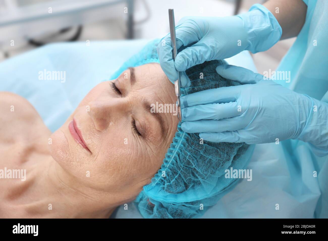 Surgeon operating female patient with scalpel at beauty salon Stock ...