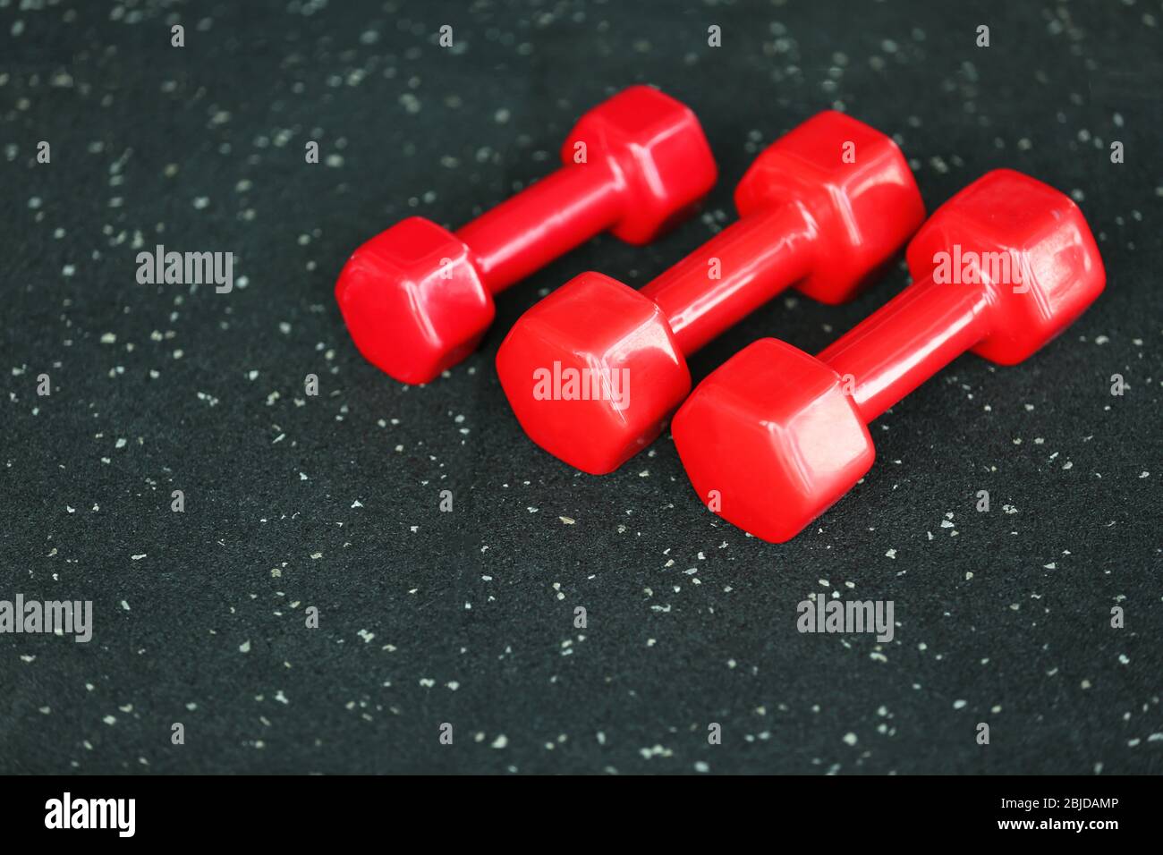 Red dumbbells on floor in gym Stock Photo - Alamy