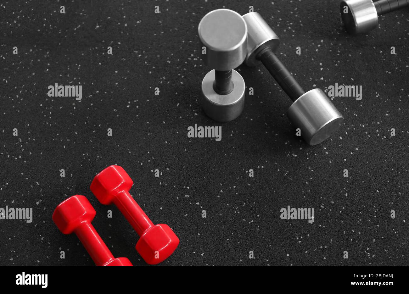 Different dumbbells on floor in gym Stock Photo - Alamy