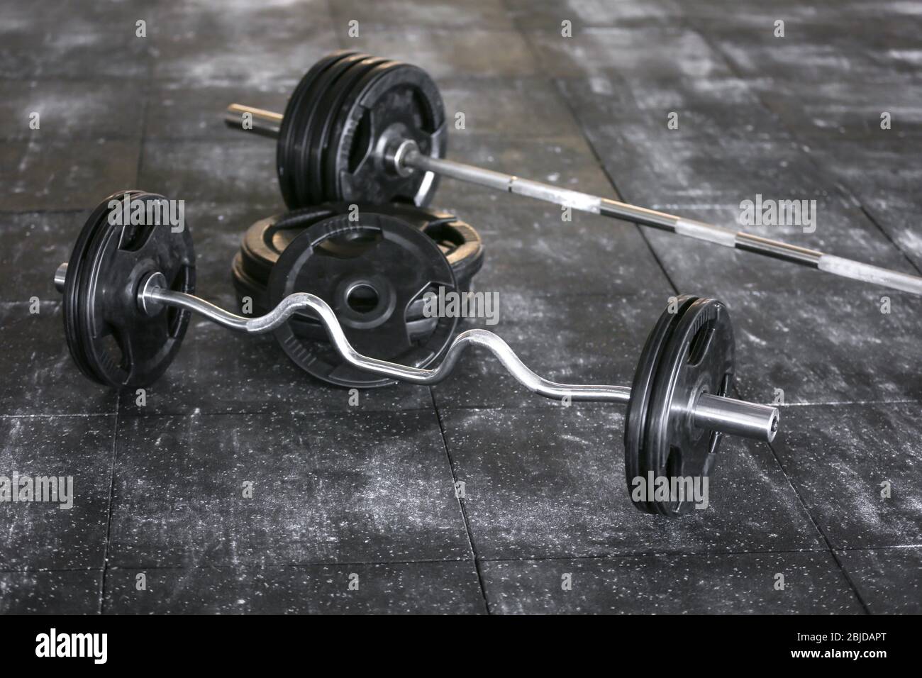 Barbells and weight plates on floor in gym Stock Photo - Alamy