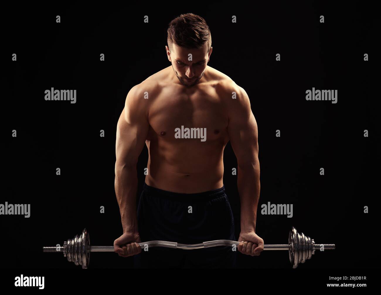 Sporty man doing exercises with barbell on black background Stock Photo ...