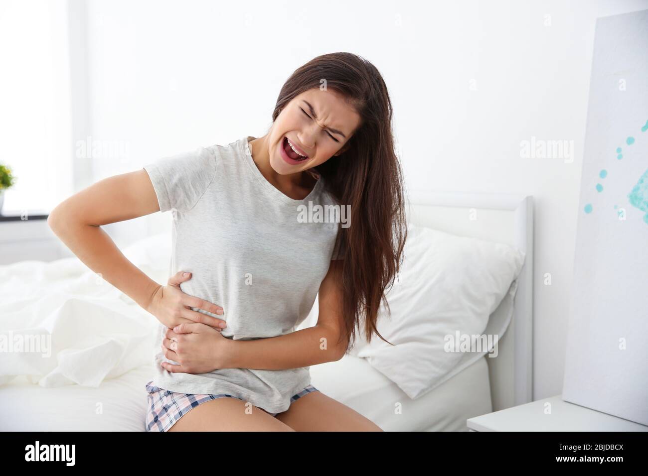 Young woman suffering pain at bedroom Stock Photo - Alamy