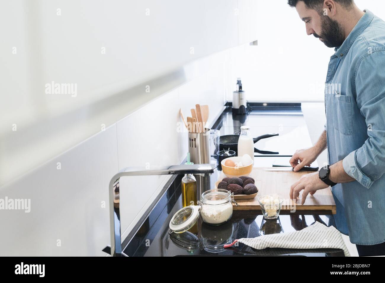 Man cooking in the kitchen in a denim shirt Stock Photo - Alamy