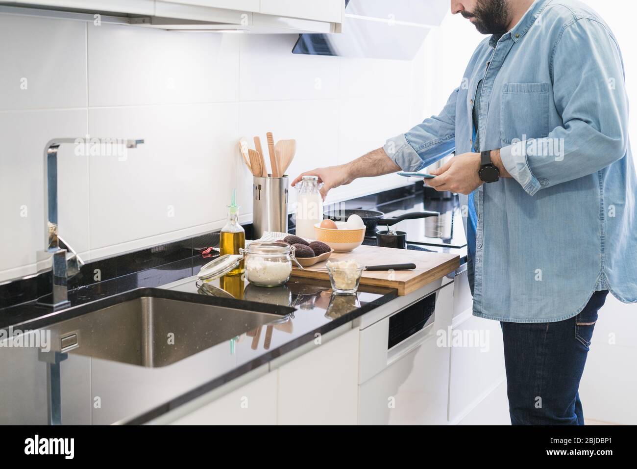 Man cooking in the kitchen in a denim shirt Stock Photo - Alamy