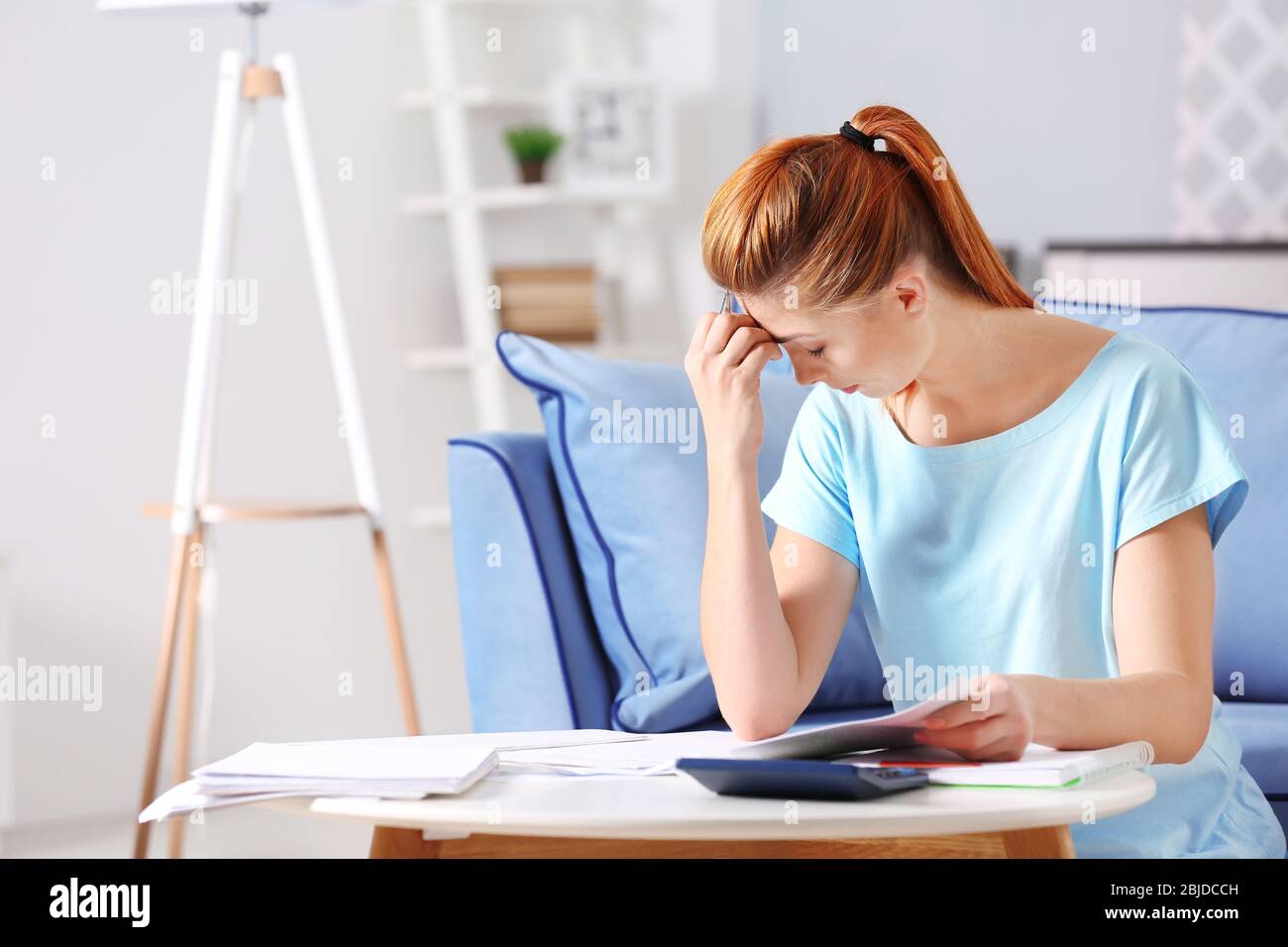 Confused young woman calculating taxes at home Stock Photo - Alamy