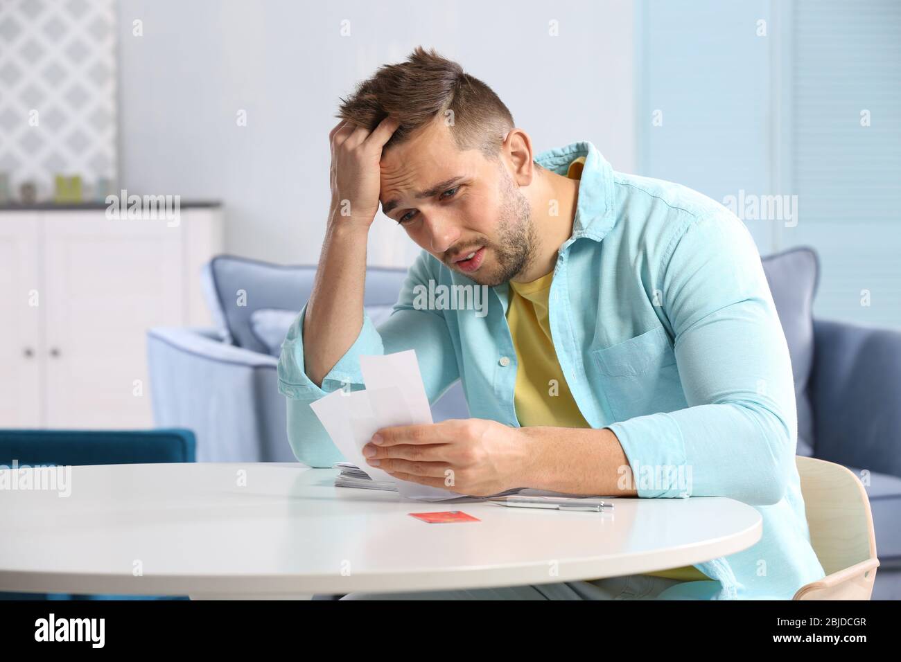 Confused young man calculating taxes at home Stock Photo - Alamy