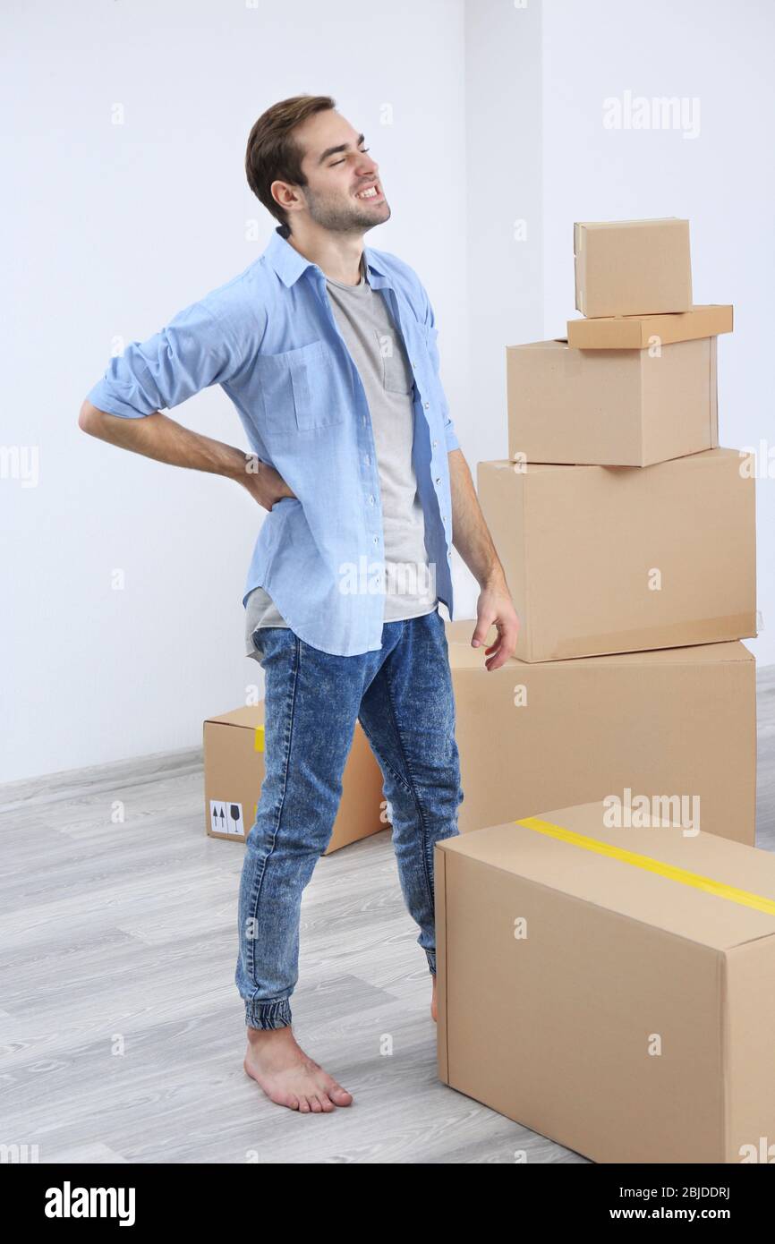 Man suffering back ache moving boxes indoors Stock Photo - Alamy