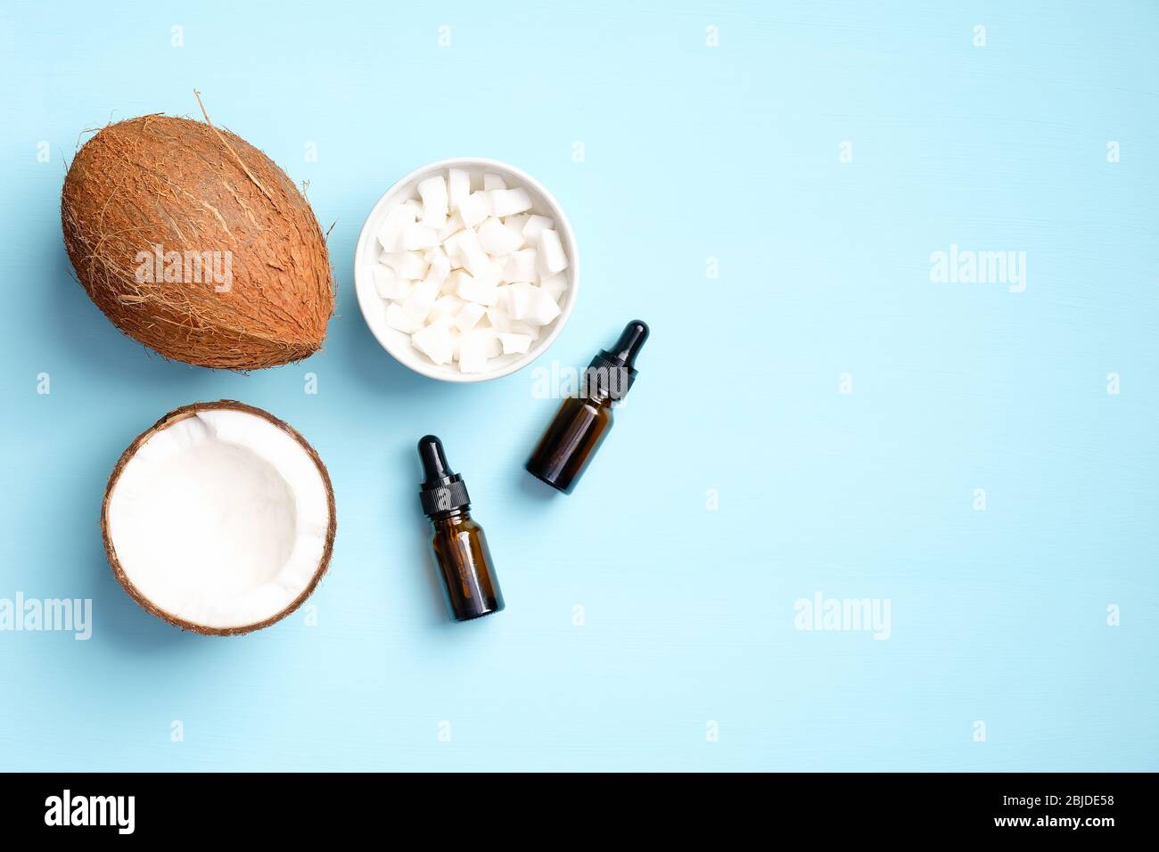 Coconut essential oil bottles with sliced coconut in bowl and half of ...