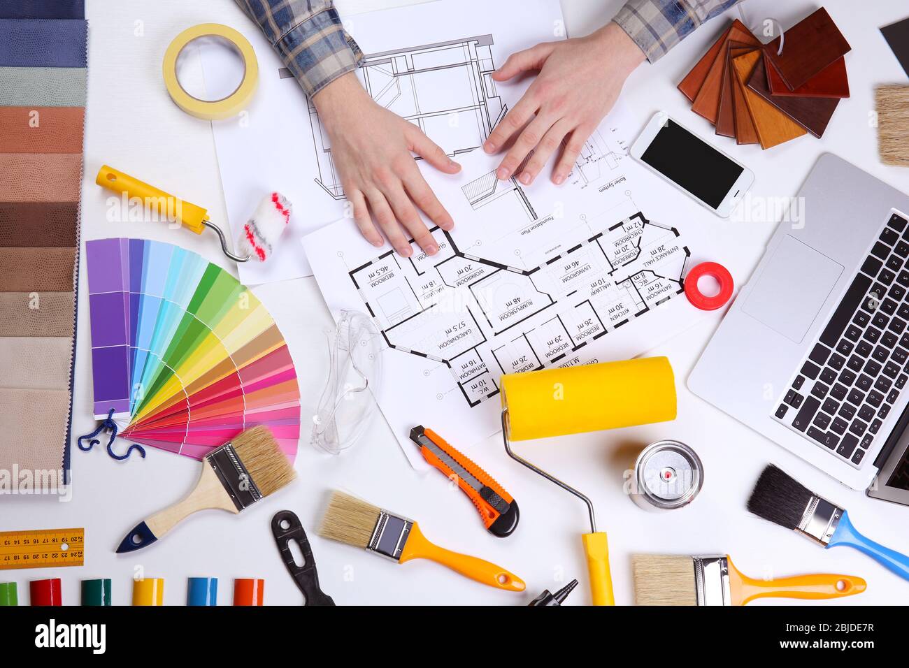 Decorator's hands on project drawing. Laptop, color swatches and tools ...