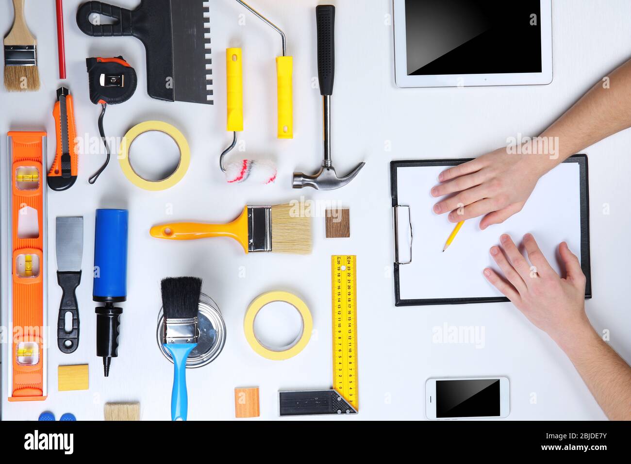 Decorator's hands with pencil and clipboard. Color swatches and tools ...