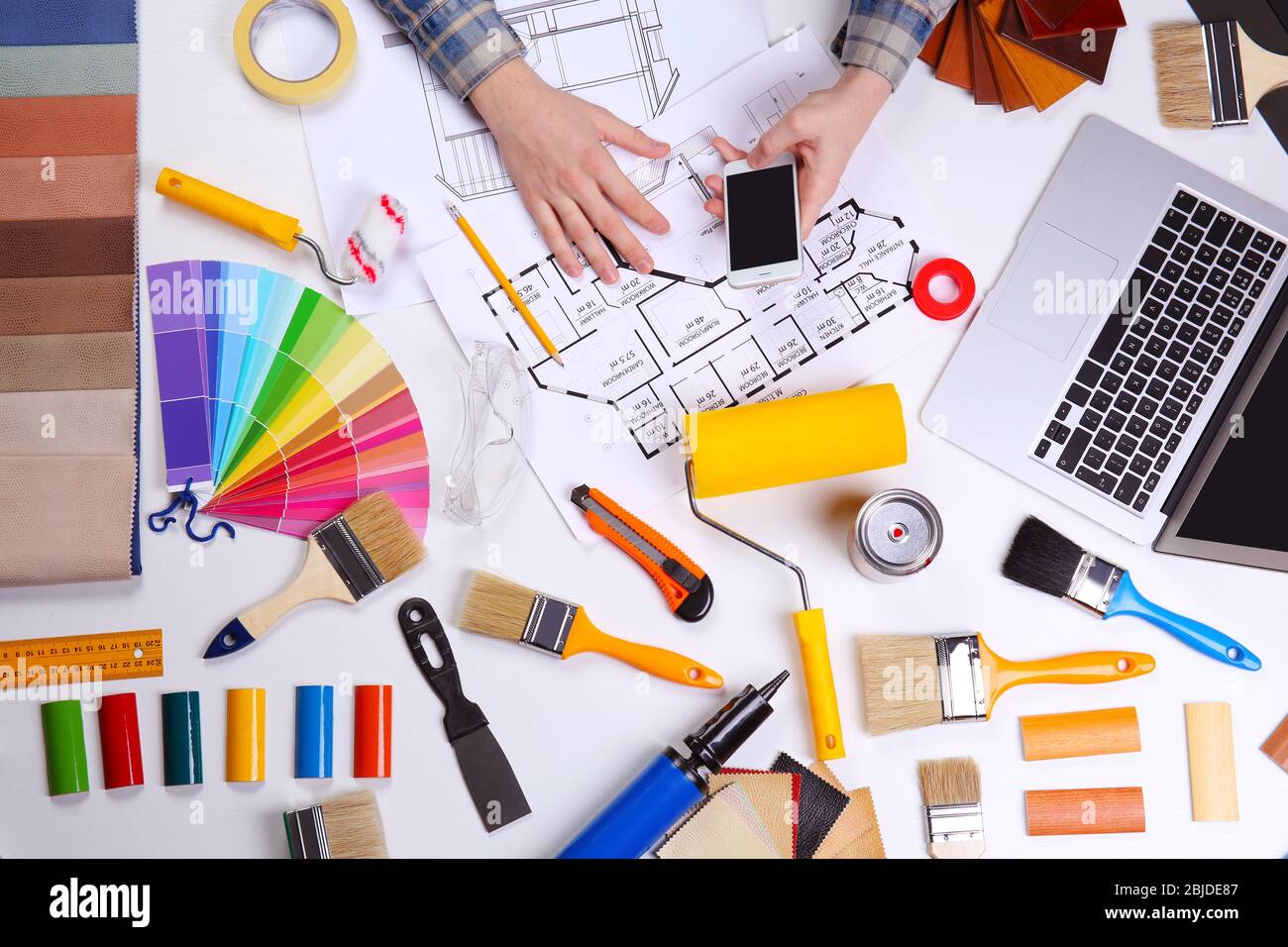 Decorator using a phone. Color swatches and painting tools all around ...