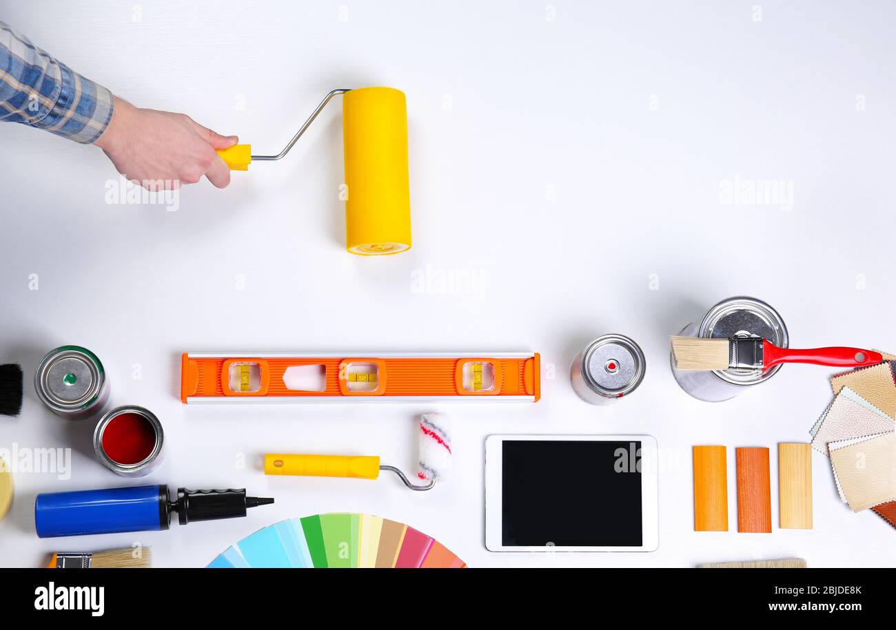 Decorator's hand with paint roller. Color swatches and tools on work ...