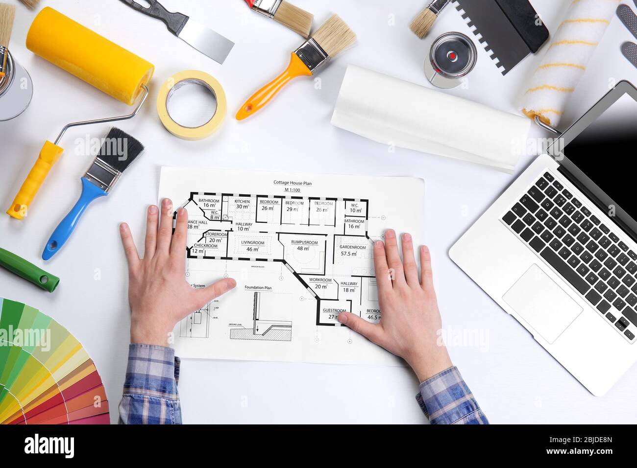Decorator's hands on project drawing. Laptop, color swatches and tools ...