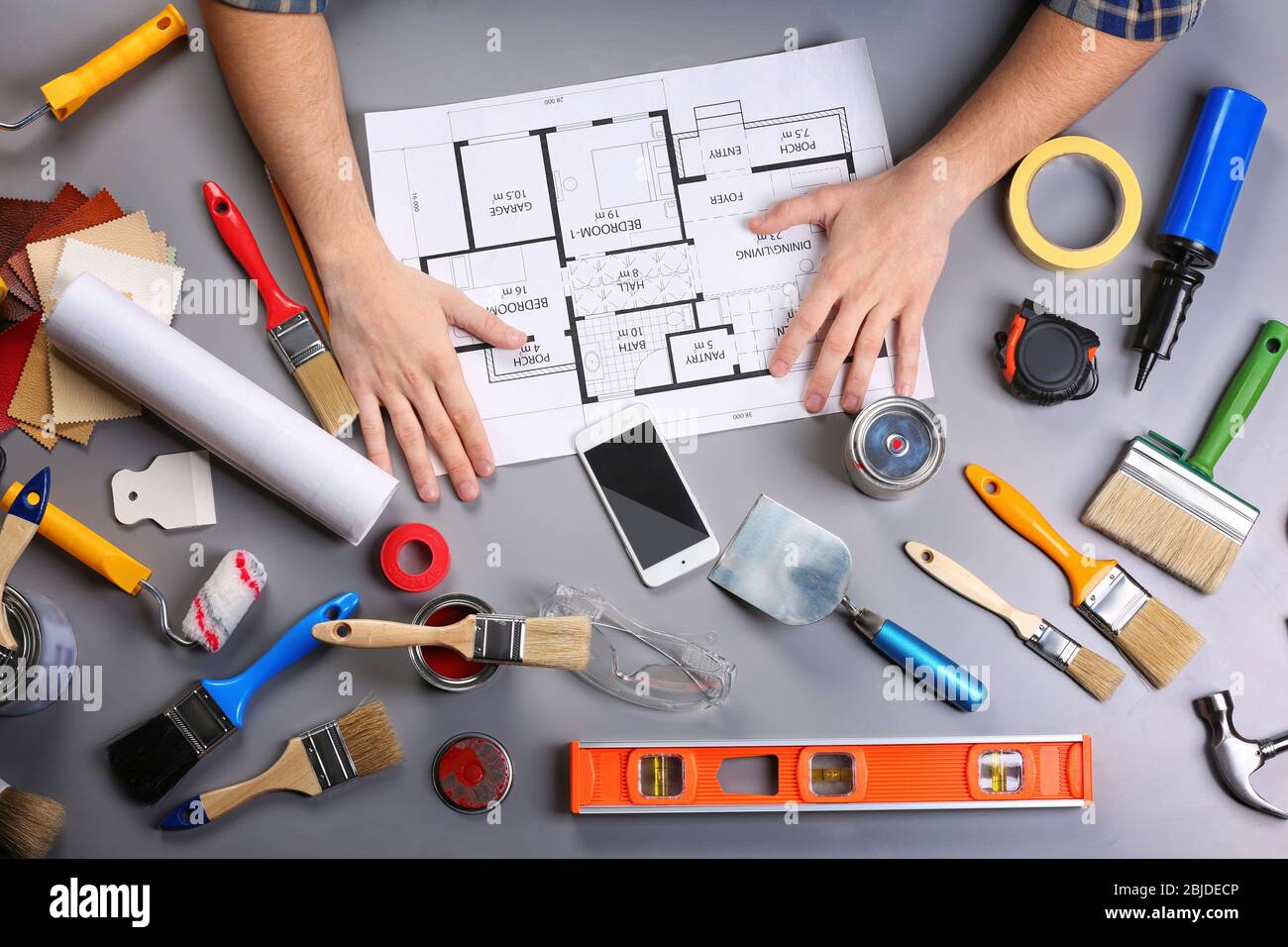 Decorator's hands on project drawing. Paint tools all around on table ...