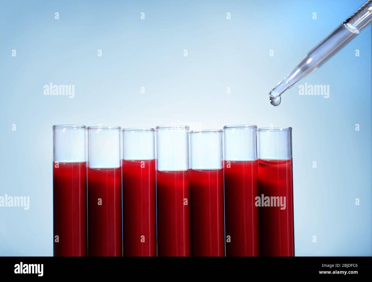 Test tubes filled with blood and glass dropper on blue blurred ...