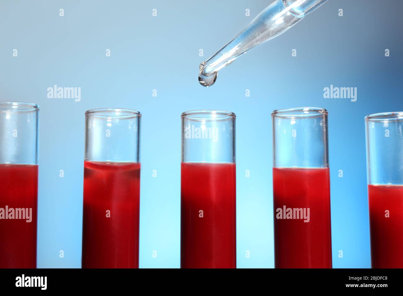 Test tubes filled with blood and glass dropper on blue blurred ...
