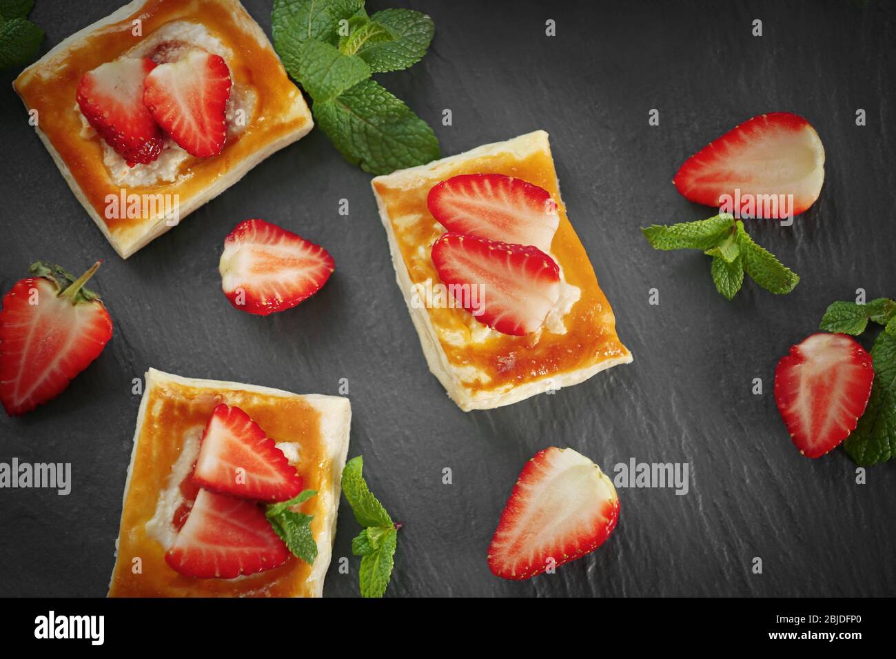 Sweet tasty pastries with fresh strawberries on textured background ...