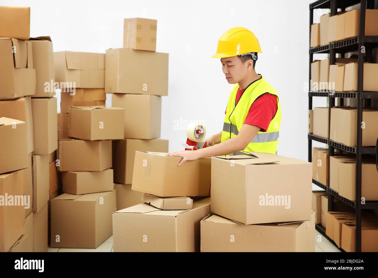 Man packing parcels with sticky tape at warehouse Stock Photo - Alamy