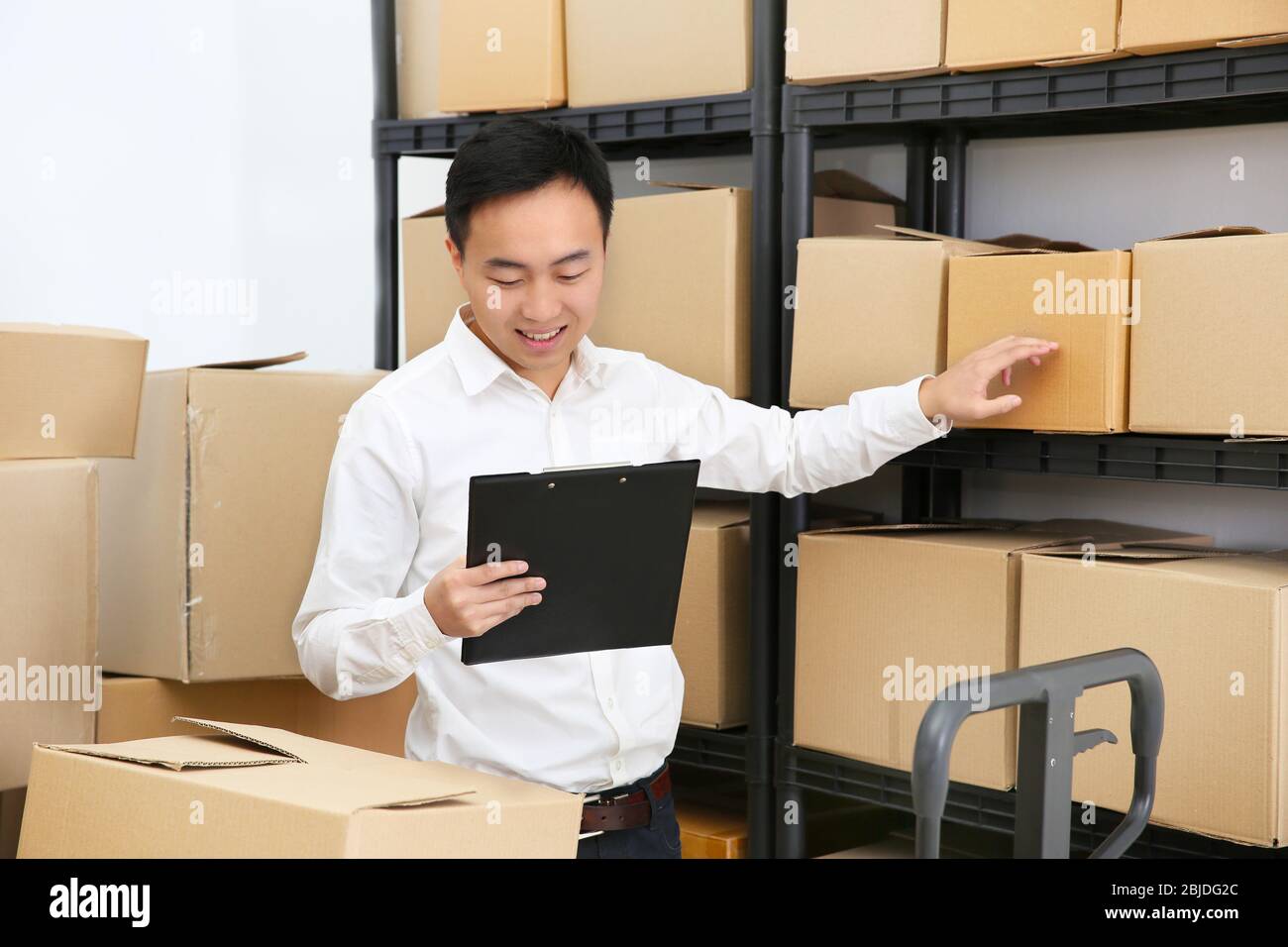 Man with clipboard checking orders at logistics company warehouse Stock ...