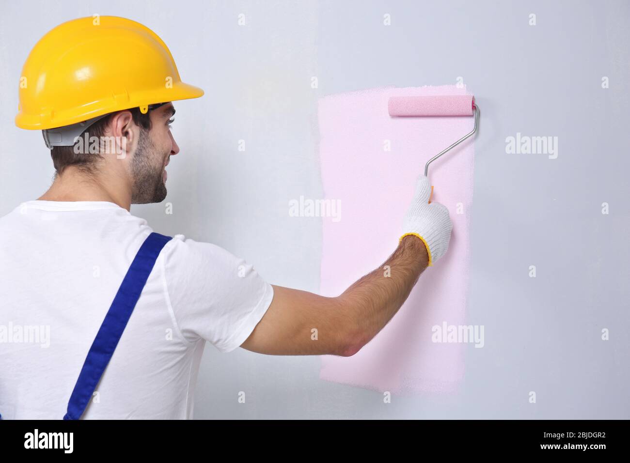 Young worker painting wall in room Stock Photo - Alamy