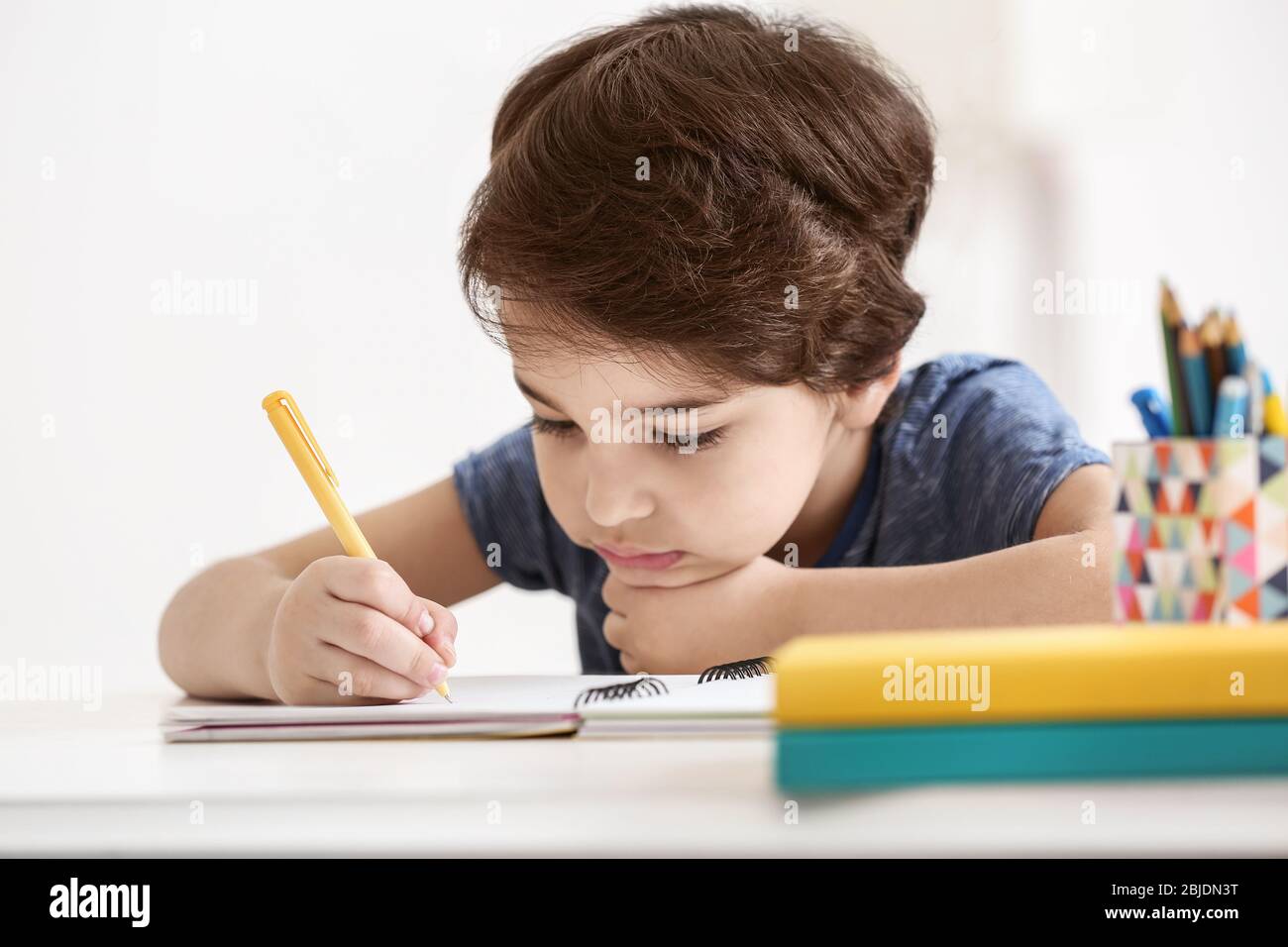 Cute little boy writing something in notebook Stock Photo - Alamy